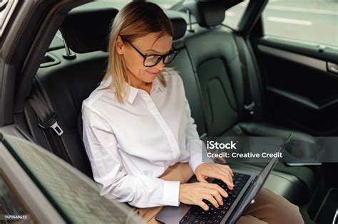사무실로 가는 길에 자동차 뒷좌석에 앉아 노트북으로 작업하는 안경을 쓴 전문 여성 분석가 45 49세에 대한 스톡 사진 및 기타