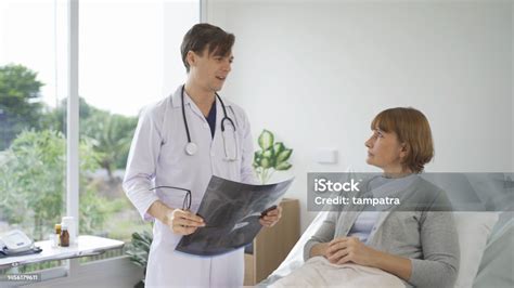 요양원에서 의료 및 건강 관리 치료를 받고 있는 병원의 침대에 누워 아픈 노인 노인 환자의 뼈 X선 스캔 필름을 보여주는 백인 의사의 초상화 사람들의 라이프 스타일 2명에