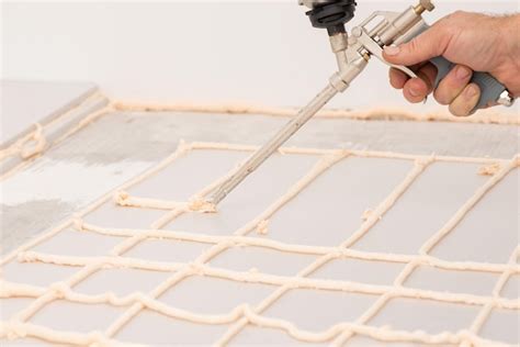 Premium Photo Worker Applying Foam With Glue Gun On Sheet Of Styrofoam For Gluing It To The