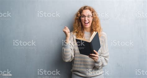 젊은 빨강 머리 여자 자랑 비명과 승리와 성공을 매우 흥분된을 축 하 하는 책을 읽고 회색 그런 지 벽에 환호 하는 감정 감정에 대한 스톡 사진 및 기타 이미지 Istock