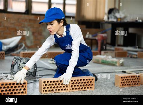 Female Builder In Blue Workwear Planning Erection Of Partition Wall In Building Under