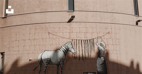 낮 동안 갈색 콘크리트 건물 옆에 서 있는 흰색과 검은색 줄무늬 긴팔 셔츠를 입은 여자 사진 Unsplash의 무료 우크라이나 이미지