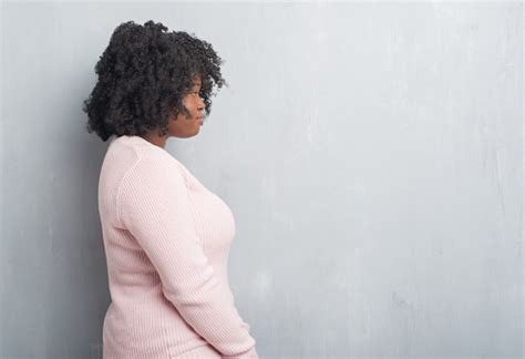 젊은 아프리카계 미국인 플러스 크기 여자 회색 그런 지 벽 쪽을 보고 겨울 스웨터를 입고 통해 자신감 미소와 자연 스러운 얼굴 프로필 포즈 긴장 인물 사진에 대한 스톡 사진