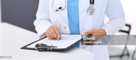 직장에서 알 수 없는 의사 여자 손 클로즈업 진료소 또는 응급 병원에서 리셉션 데스크 근처에 서 있는 동안 여성 의사는 의료 양식을 작성 의학 및 의료 개념 간호사에 대한