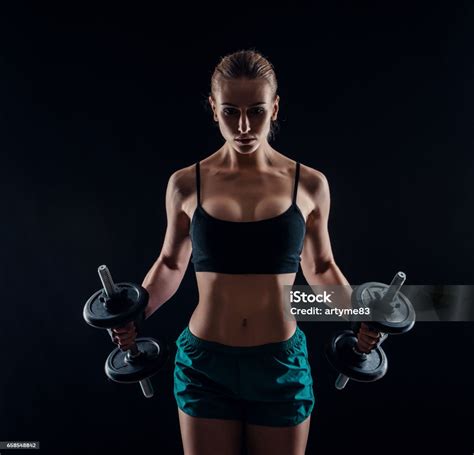 검은 배경에 아령으로 운동을 하 고 스포츠에서 피트 니스 젊은 여자의 초상화 검게 그을린된 섹시 한 운동 소녀입니다 좋은 스포티 한 여성의 몸 가냘픈에 대한 스톡 사진 및