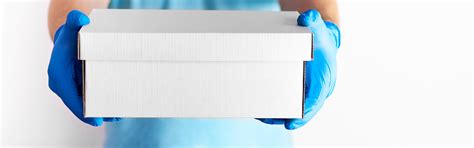 파란 의료 장갑을 낀 남성의 손은 하얀 바탕에 하얀 판지 상자를 들고 있다 전염병에서 코로나 바이러스 2019ncov에 대한 배달 비접촉식 배달 검역 중 물품 배달의 개념