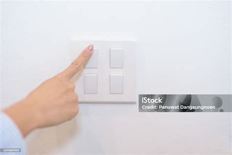 집 방의 흰색 벽에 전등 스위치를 켜기 위해 암컷 손가락을 밀고 있습니다 여자 손 끄기 조명 스위치 에너지 절약 에너지 전력 제어 전기 생태 환경 및 라이프 스타일 개념