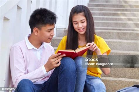 야외 장소에서 계단을 앉아있는 아시아 학생 두 사람이 책과 노트북을 사용 하 여 매력적인 웃는 계단 및 층계에 대한 스톡 사진 및 기타 이미지 Istock
