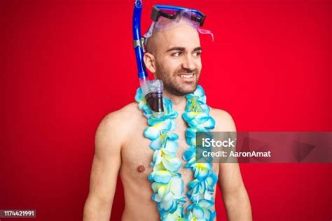 다이빙 스노클 링 고글과 하와이 레이 꽃을 입고 고립 된 빨간 배경 위에 얼굴을 미소와 함께 옆으로 바라보며 자연스러운 표정을 짓고 있습니다 자신감 있게 웃고 있습니다