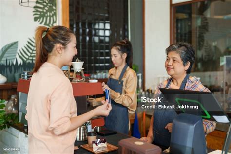 연로한 어머니는 테이크아웃 기계 카운터에 서 있고 카페에서 음식 음료를 주문하는 아름다운 고객들과 함께 바리스타가 음료를 만들고