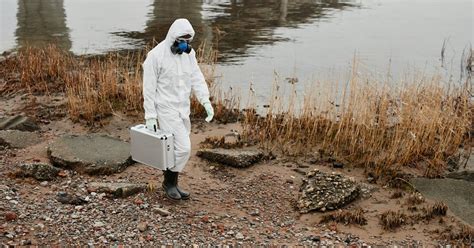방호복을 입은 노동자가 샘플 케이스 산업 폐기물 개념 복사 공간을 들고 야외에서 물가를 걷고 있다 사진 Unsplash의 화학 공장 이미지
