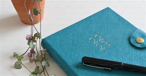 화분 옆에 펜이 있는 파란색 공책 사진 Unsplash의 의제 이미지