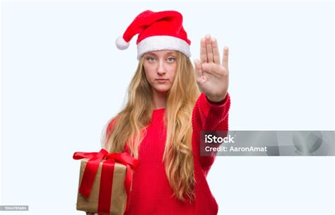 심각 하 고 자신감 표현 방어 제스처 정지 표시를 하 고 오픈 손으로 산타 클로스 모자를 입고 금발 십 대 여자 경계 표지에 대한 스톡 사진 및 기타 이미지 Istock
