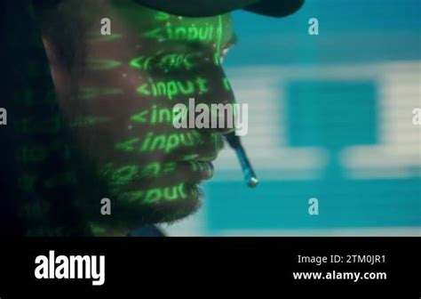 Hacker With Headset Working On A Computer A Line Of Program Code Is Reflected On His Face A