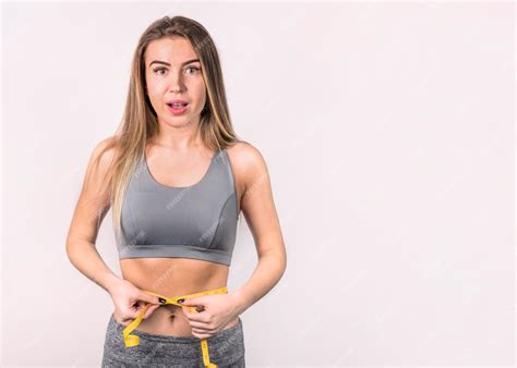 Удивленная привлекательная стройная женщина измеряет талию Бесплатно Фото