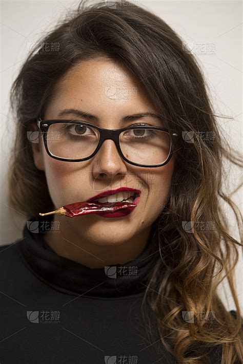 涂着红色口红戴着眼镜咬着辣椒的女人