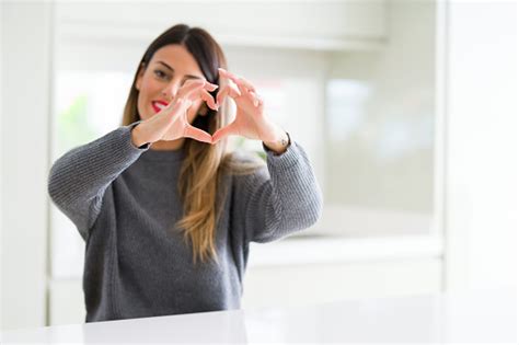 집에서 겨울 스웨터를 입고 젊은 아름 다운 여자 마음 기호와 손으로 모양을 보여주는 사랑에 웃 고 낭만적인 개념입니다 가정 생활에 대한 스톡 사진 및 기타 이미지 Istock