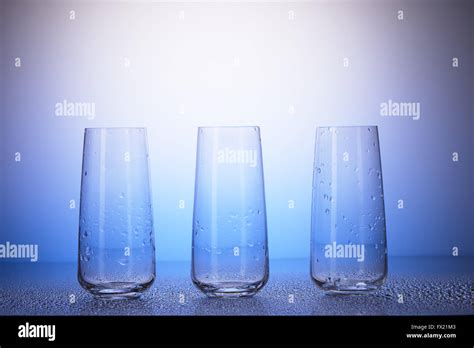 Three Empty Drinking Glasses With Reflection In Drops Of Water On White
