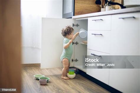 귀여운 호기심 많은 백인 아기가 부엌에서 찬장 문을 열고 콘텐츠를 탐색한다 12 17 개월에 대한 스톡 사진 및 기타 이미지 12 17 개월 12 23 개월 가구