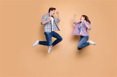 두 사람 미친 여자 남자 점프 높은 축하 최고의 승리 를 축하하는 전체 길이 사진 주먹 흥분 착용 캐주얼 격자 무늬 청바지 옷