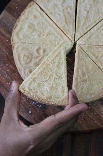 엉겅퀴 금형 패턴 디테일 황금 갈색 오븐에서 신선한 삼각형으로 잘라 높은 전망을 보여주는 둥근 나무 도마 위에 둥근 나무 도마 라운드 의 삼각형 조각을 들고 인식 할 수없는