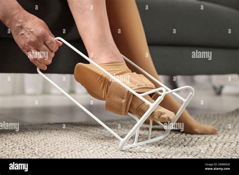 Woman Putting On Compression Tights With Stocking Donner In Living Room Closeup Prevention Of