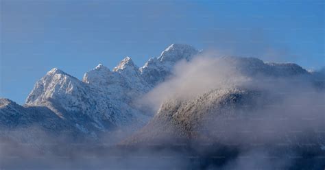 푸른 하늘 아래 눈과 구름으로 뒤덮인 산 사진 Unsplash의 이미지