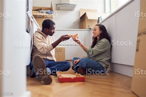 젊은 부부는 제거 상자와 부엌에서 피자를 먹고 바닥에 앉아 새로운 집으로 이동 축하 새 집으로 이사에 대한 스톡 사진 및 기타
