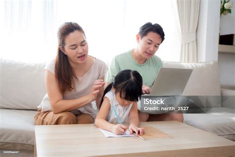 어머니가 숙제를 가르치는 행복한 가족 딸과 아버지가 집 거실 소파에서 노트북으로 일하는 모습 엄마가 아이와 함께 학업 라이프스타일 교육을 설명하는 행복한 가족 3 명에 대한