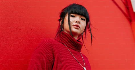 빨간 스웨터를 입은 여자가 빨간 벽에 기대어 서 있다 사진 Unsplash의 초상 이미지