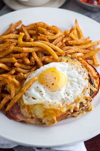 크로크 마담 또는 무슈 아침 식사 또는 브런치 좋아하는 토스트 튀긴 계란 햄 치즈 홀란데이즈 소스를 얹습니다 감자 해시가 있는 나무 도마에 제공됩니다 클래식 한 프랑스