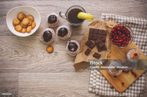 리넨 냅킨 냅킨에 가벼운 나무 탁상에 두 머핀 깨진된 초콜릿 바와 작은 나무 쿠키 그릇 옆에 밝은 붉은 열매와 함께 보드 절단이