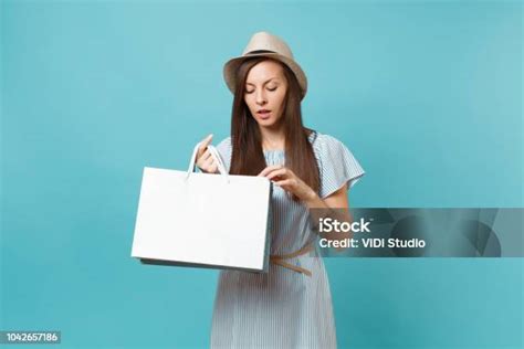 세로 행복 여름 패키지 가방을 들고 드레스 밀 짚 모자 구매 후 블루 파스텔 배경에 고립 쇼핑에 웃는 아름 다운 백인 여자 흥분 광고에 대 한 공간을 복사 가방에 대한 스톡