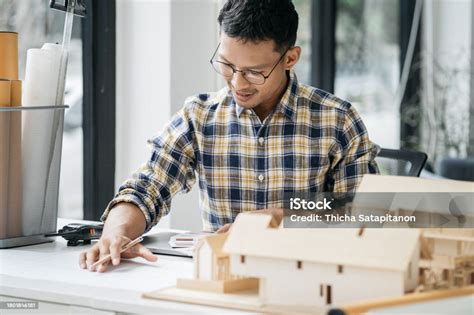 테이블에서 작업하는 건축가 또는 엔지니어는 비즈니스 건축 프로젝트를 위한 종이 계획에서 그리기 도구를 사용합니다 40 44세에