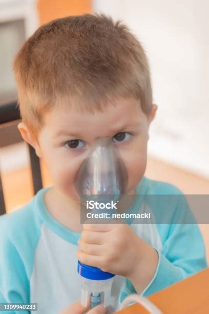 흡입 치료 중 분무기를 사용하는 어린 소년 집에서 분무기로 흡입을 하는 어린 소년 천식 예방을 위해 흡입을 복용 하는 소년의 초상화를 닫습니다 2 3 살에 대한 스톡 사진