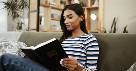 여자여 성경 공부를 하고 집 소파에서 독서 지식 및 영적 안내를 위한 성경 공부를 위해 미소 짓습니다 아파트에서 복음의 종교 학습 및 지혜가 담긴 사람 소녀 및 기독교 책