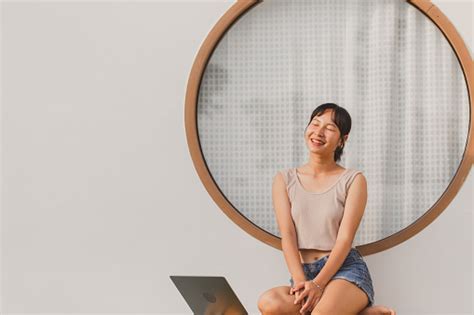 젊은 매력적인 아시아 프리랜서 여성은 여름 방학 동안 노트북 컴퓨터로 일하는 창문 집 앞 벤치에 앉아 있습니다 행복한 아시아 십대 학생 온라인 학습 20 24세에 대한 스톡