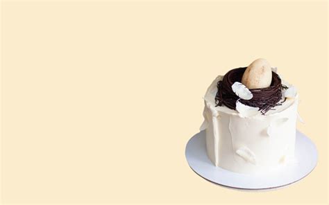 초콜릿 새 둥지 달걀 깃털로 장식된 우아한 부활절 케이크 복사 공간이 있는 베이지색 배경입니다 수평 방향 0명에 대한 스톡 사진