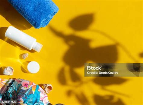 밝은 노란색 모래 배경에 수건 수영복 및 자외선 차단제를 여행자를위한 액세서리가있는 여름 배경 밝은 햇빛과 여름 배경 여행 및