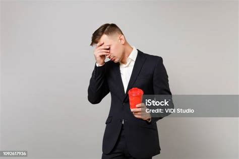 소진 팜 보류 종이 컵 커피 또는 차 회색 배경에 격리로 얼굴을 덮고 머리에 손을 넣어 하는 젊은 사업가 성과 경력 부 비즈니스