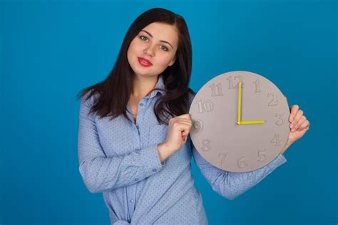 Premium Photo Cute Woman With Grey Clock With Yellow Arrow In Her Hands Is Standing Against Of