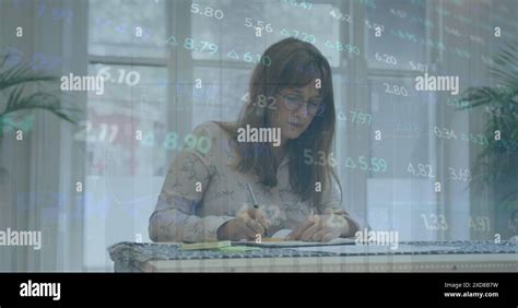 Image Of Stock Market Data Processing Against Thoughtful Caucasian Woman Taking Notes At Office