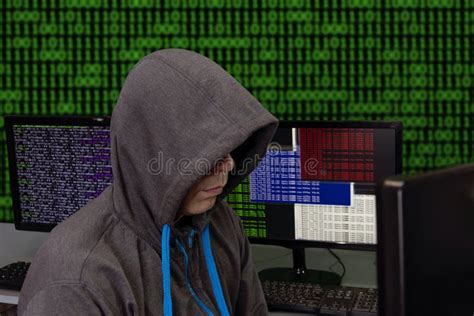 A Hacker Sits Behind Computer Monitors On An Abstract Background