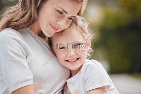 阳光明媚的日子里，慈爱的白人母亲坐在外面拥抱她可爱的女儿。高清摄影大图 千库网
