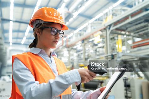 안전 장비를 착용한 미소 짓는 여성이 공장 환경에서 바코드 스캐너로 문서를 스캔합니다 25 29세에 대한 스톡 사진 및 기타 이미지 25 29세 Stem 주제 검사