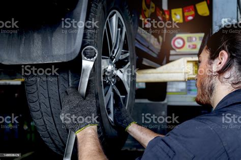 차고에서 휠 타이어를 점검하는 자동차 정비사 자동차 서비스 센터에서 고객 차량을 점검 및 수리하는 자동차 서비스 기술자 차량