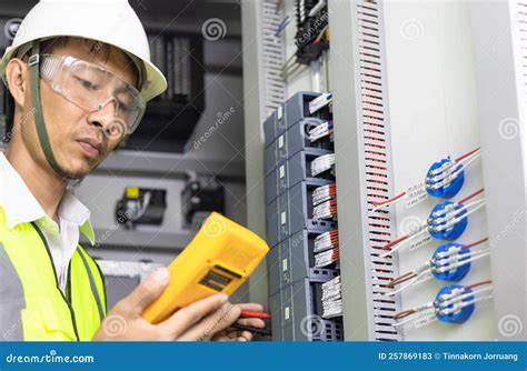 A Male Electrician Works In A Switchboard Electrical Terminal Box Control Panel With Magnetic