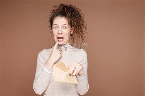 喜出望外的年轻女士的室内肖像拿着工艺纸信封高清图片下载 正版图片506373568 摄图网