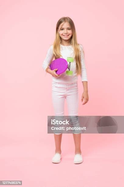 시원한 힙스터 분홍색 배경에 스케이트 보드를 들고 귀여운 작은 힙스터 힙스터 스타일과 표정으로 웃고 있는 사랑스러운 작은 스케이터 손에 보라색 페니 보드와 행복한 힙스터