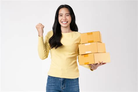미소 짓는 아시아 여성은 주먹을 꽉 쥐고 골판지 상자를 들고 승리를 축하하며 흰색 배경에 성공을 표현한다 25 29세에 대한 스톡 사진 및 기타 이미지 Istock